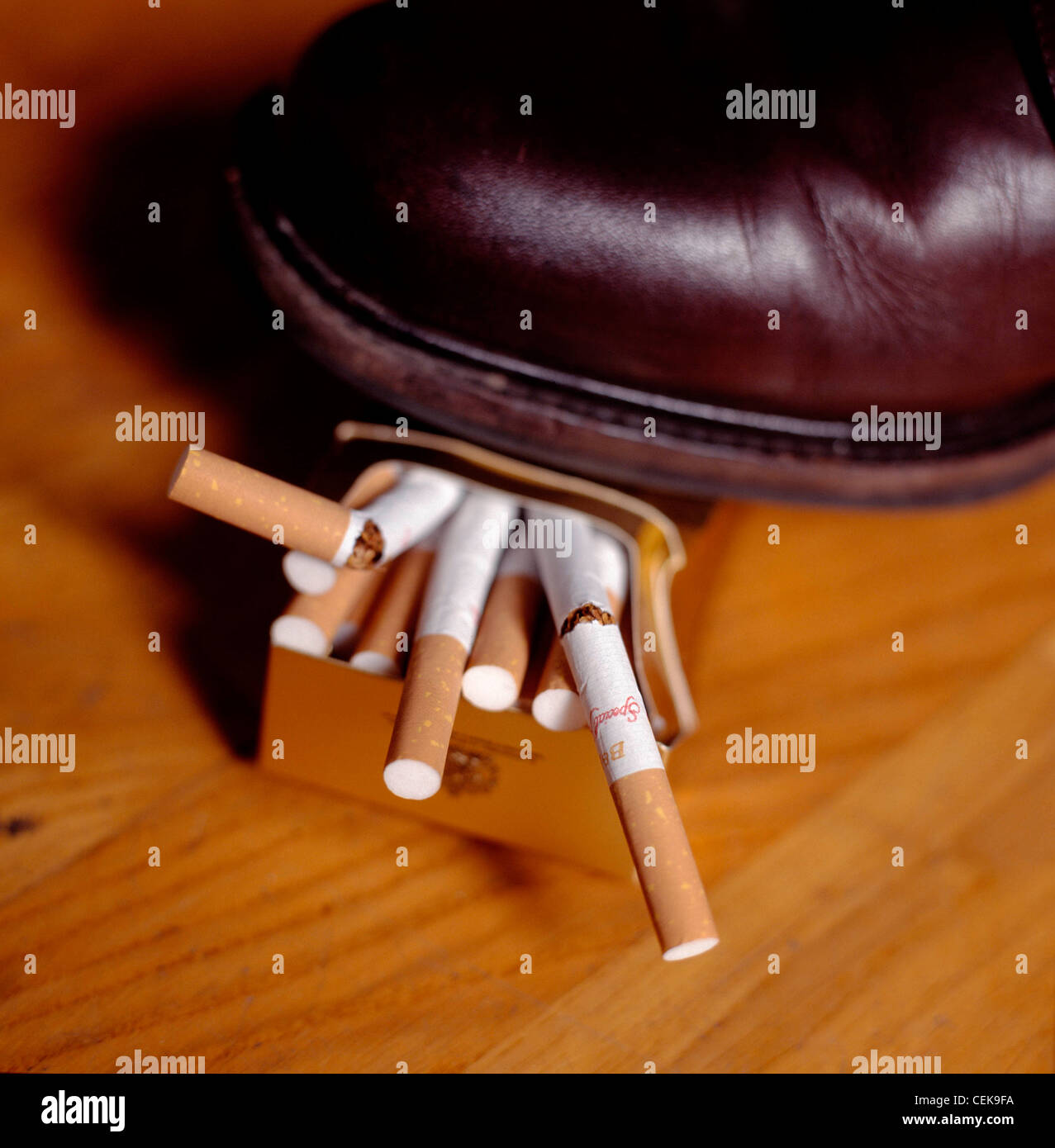 Close up of male foot wearing leather shoe standing on packet of broken ...