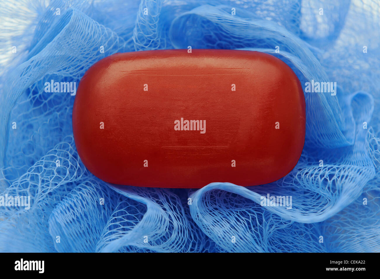 A red bar of soap, on a blue nylon mesh shower puff Stock Photo - Alamy
