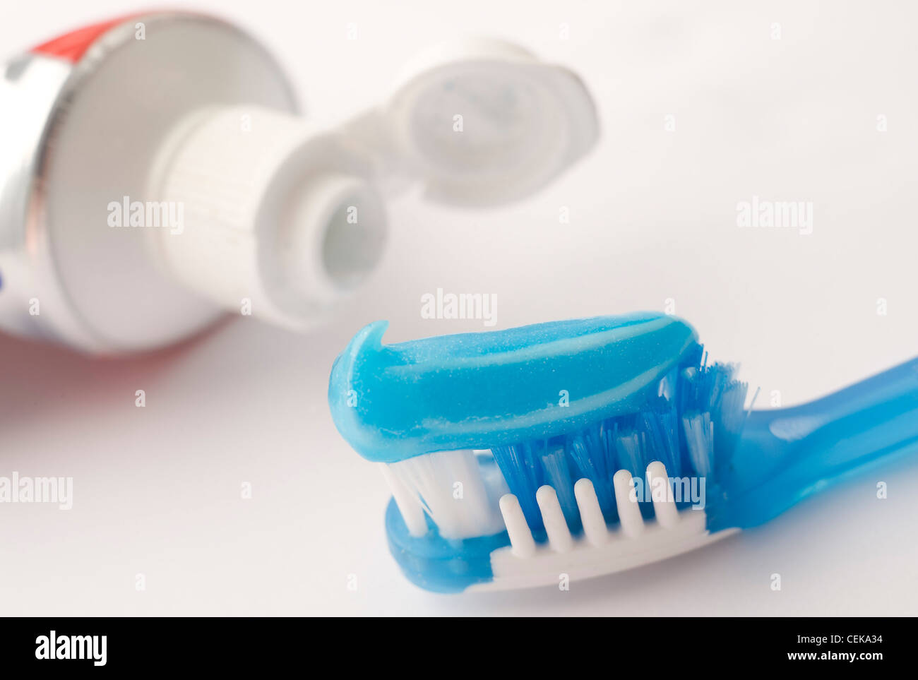 A crumpled tube of toothpaste, with white and blue striped toothpaste ...
