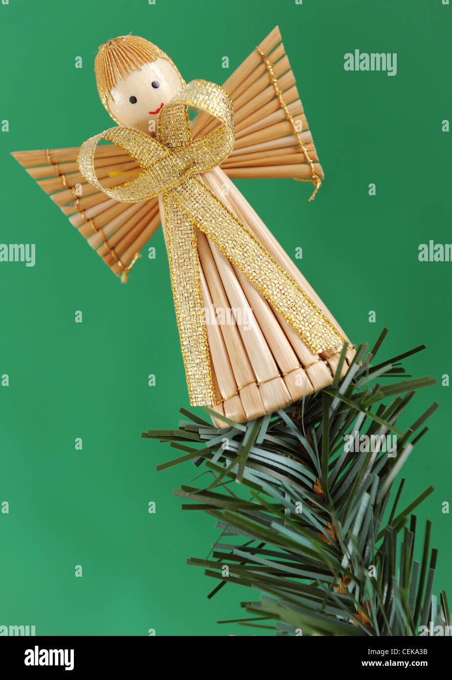 A straw angel shaped tree decorations at the top of a christmas tree ...
