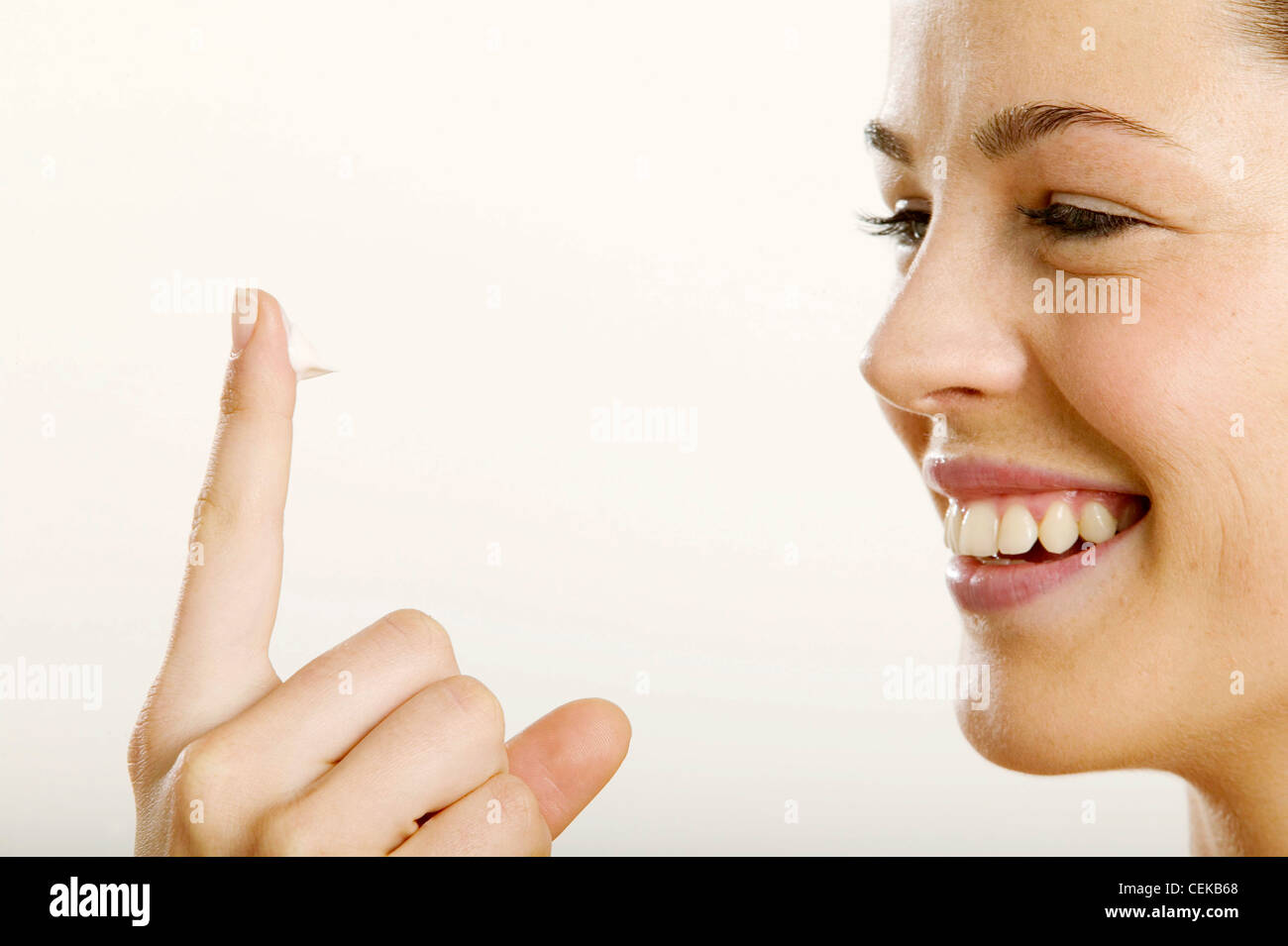 Female with holding up finger with blob of moisturiser on looking to ...