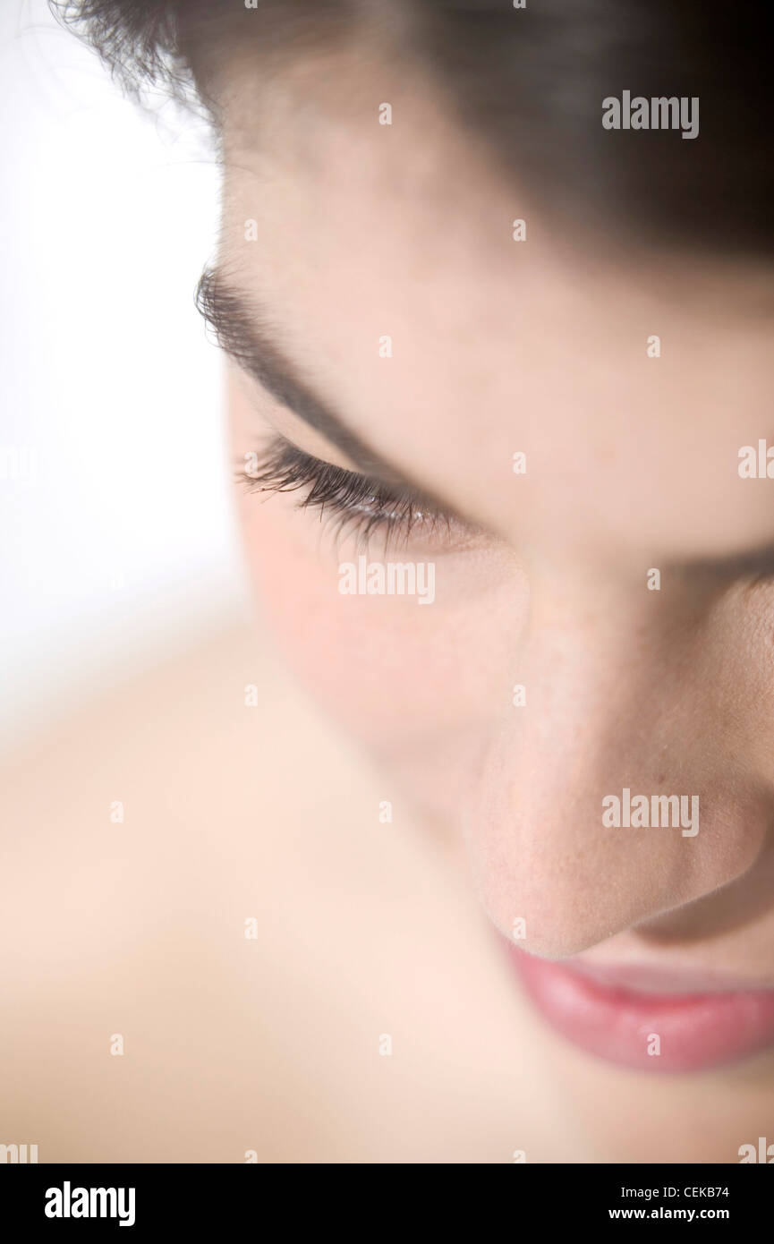 Close up of female face looking down smiling , against white background ...