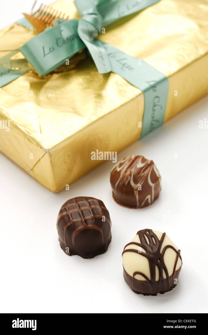 A box of chocolates wrapped in gold foil paper and tied with green ...