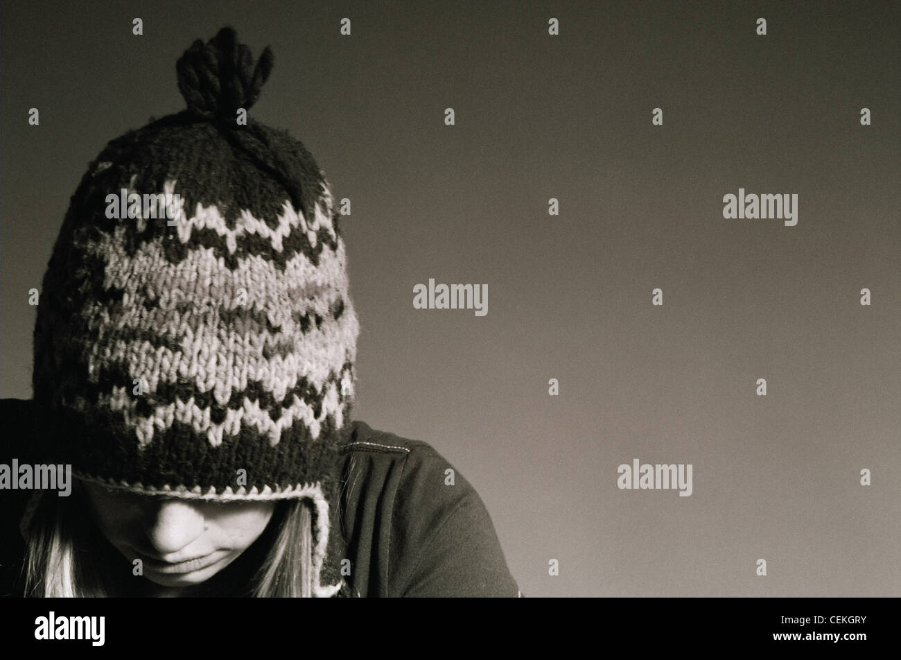 Head and shoulders of female wearing wooly hat pulled down over face ...