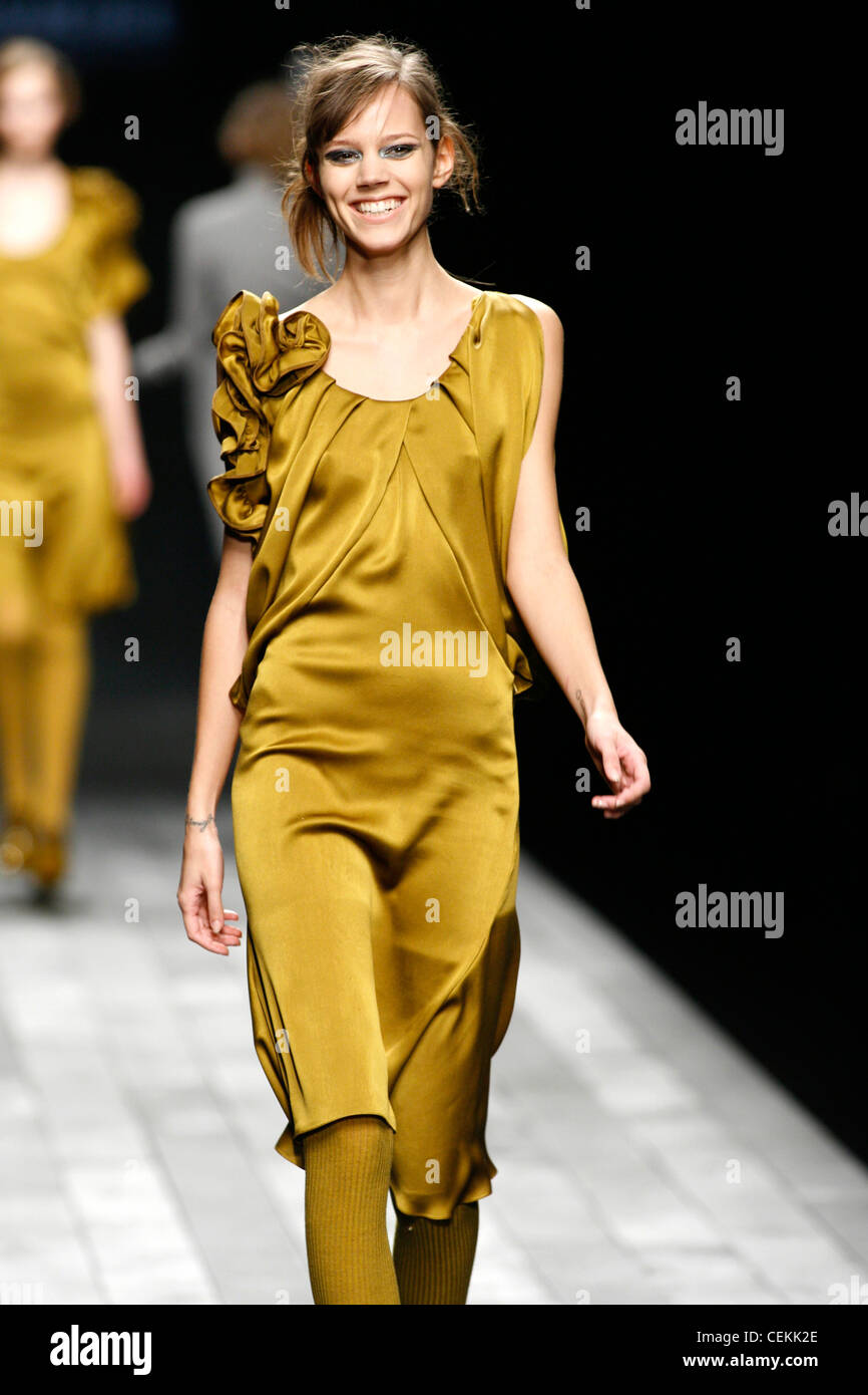 Model wearing gold satin dress with twisted detail on shoulder Stock ...