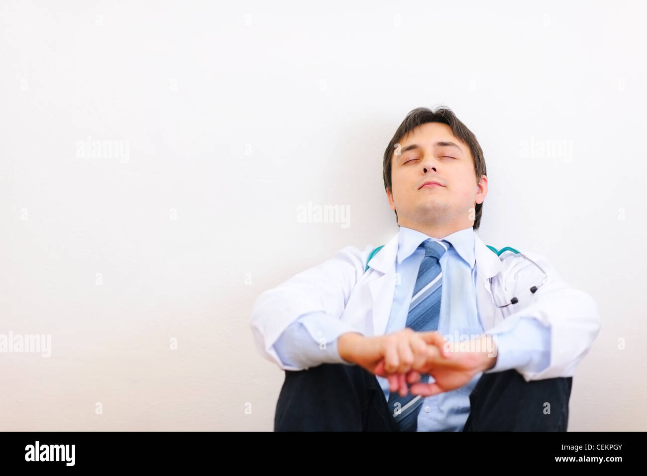 Tired medical doctor sitting on floor and relaxing Stock Photo - Alamy