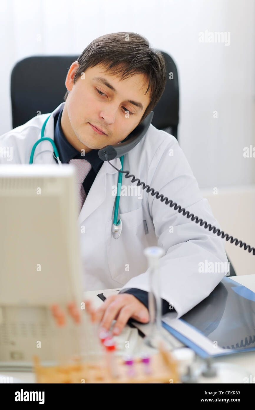 Busy medical speaking phone and working on computer Stock Photo - Alamy