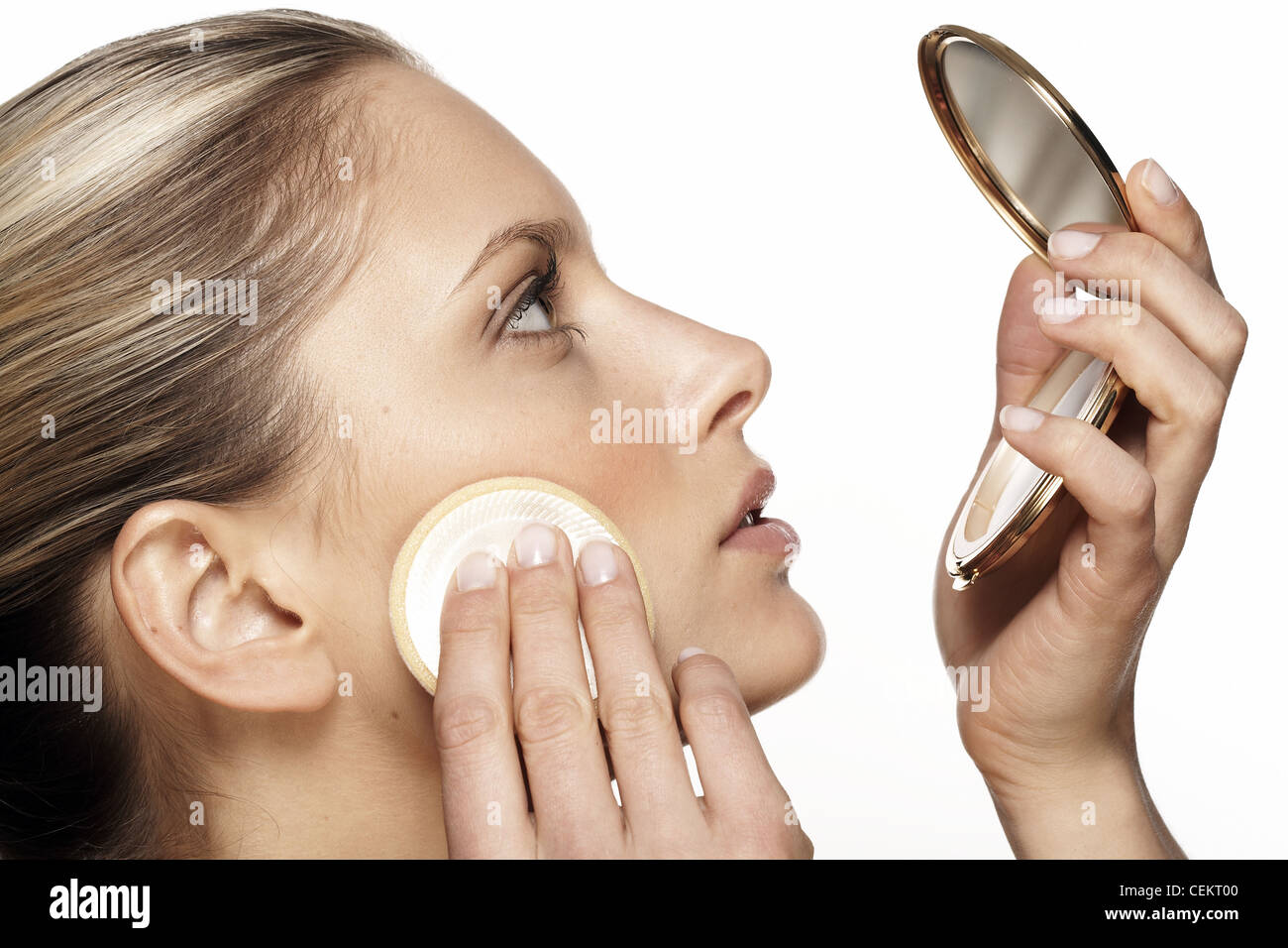 Female applying powder to face holding compact Stock Photo - Alamy