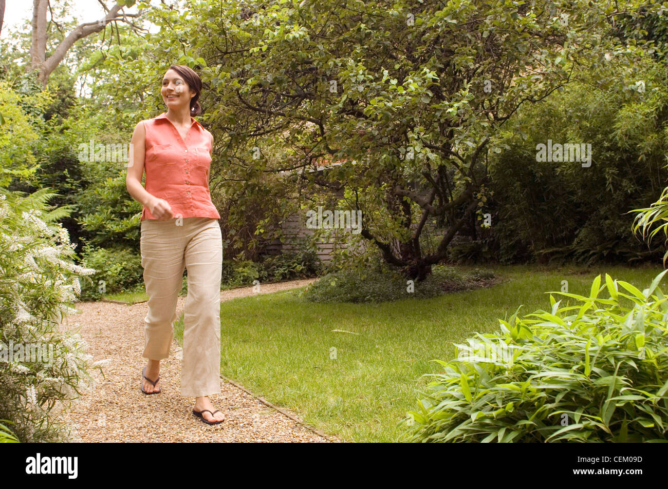 Female walking down a gravel path in a garden Stock Photo - Alamy