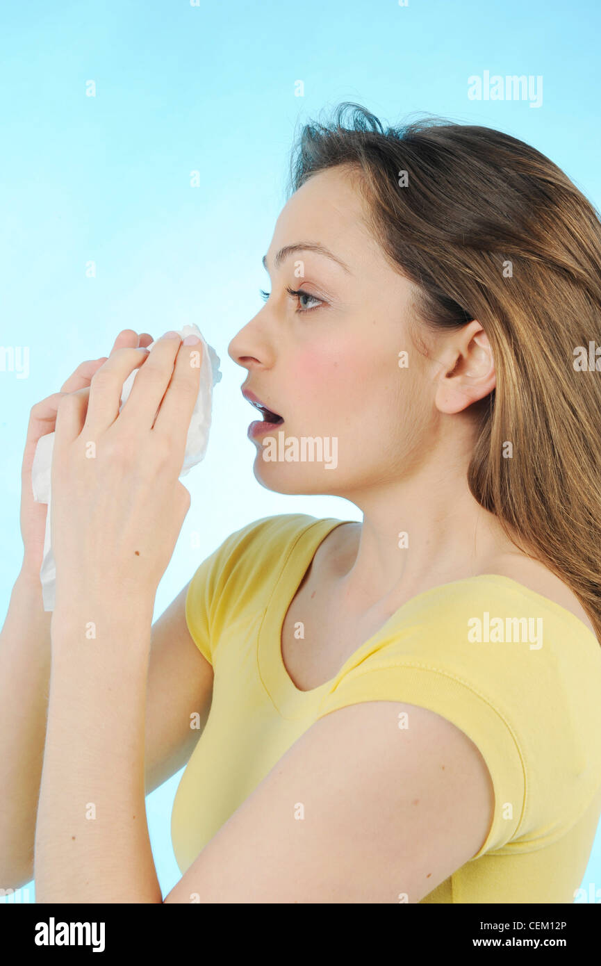 Female with brunette hair, wearing a yellow t shirt, sneezing into ...