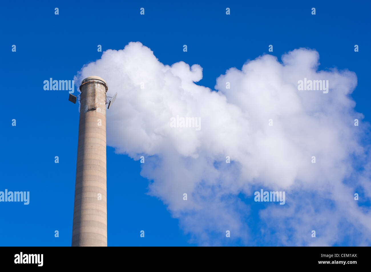 Industrial chimney or smokestack emitting gases visible against blue ...