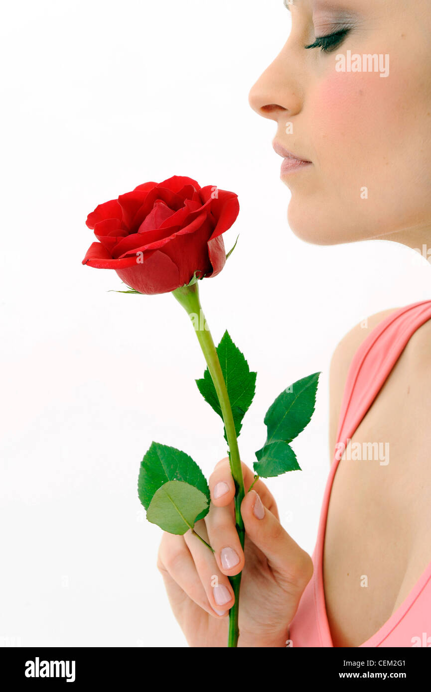 Female wearing a pink vest, holding a single red rose with one hand ...