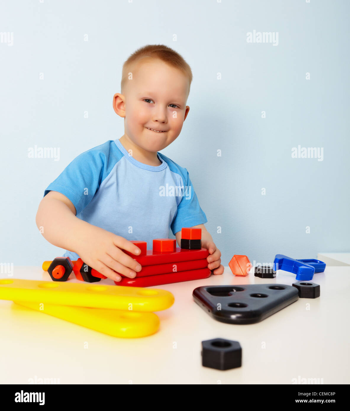 A little boy sitting at a table. Playing Stock Photo - Alamy