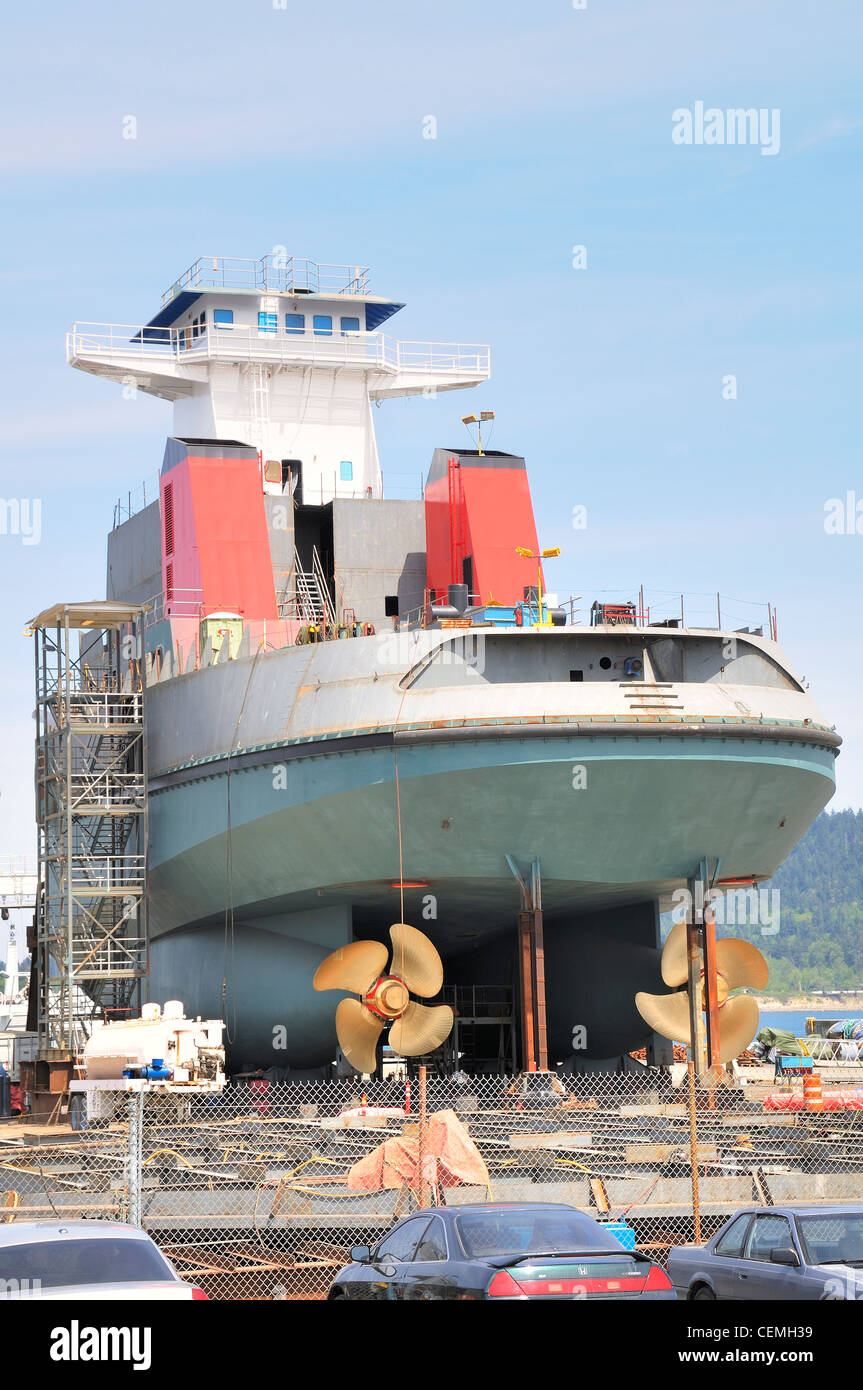 A large ship in dry dock showing the stern with propellers or screws ...