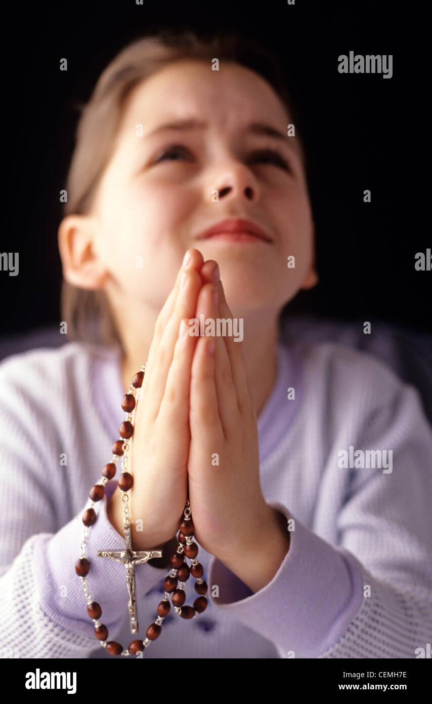 Young girl in prayer holding a rosary in her hands Stock Photo - Alamy