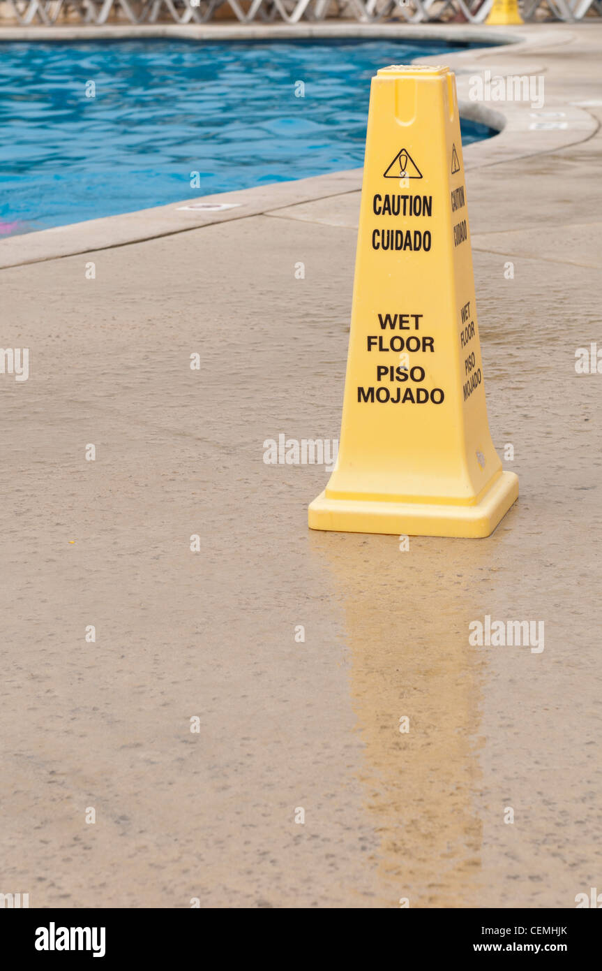 yellow caution sign regarding slippery surface next to a swimming pool ...