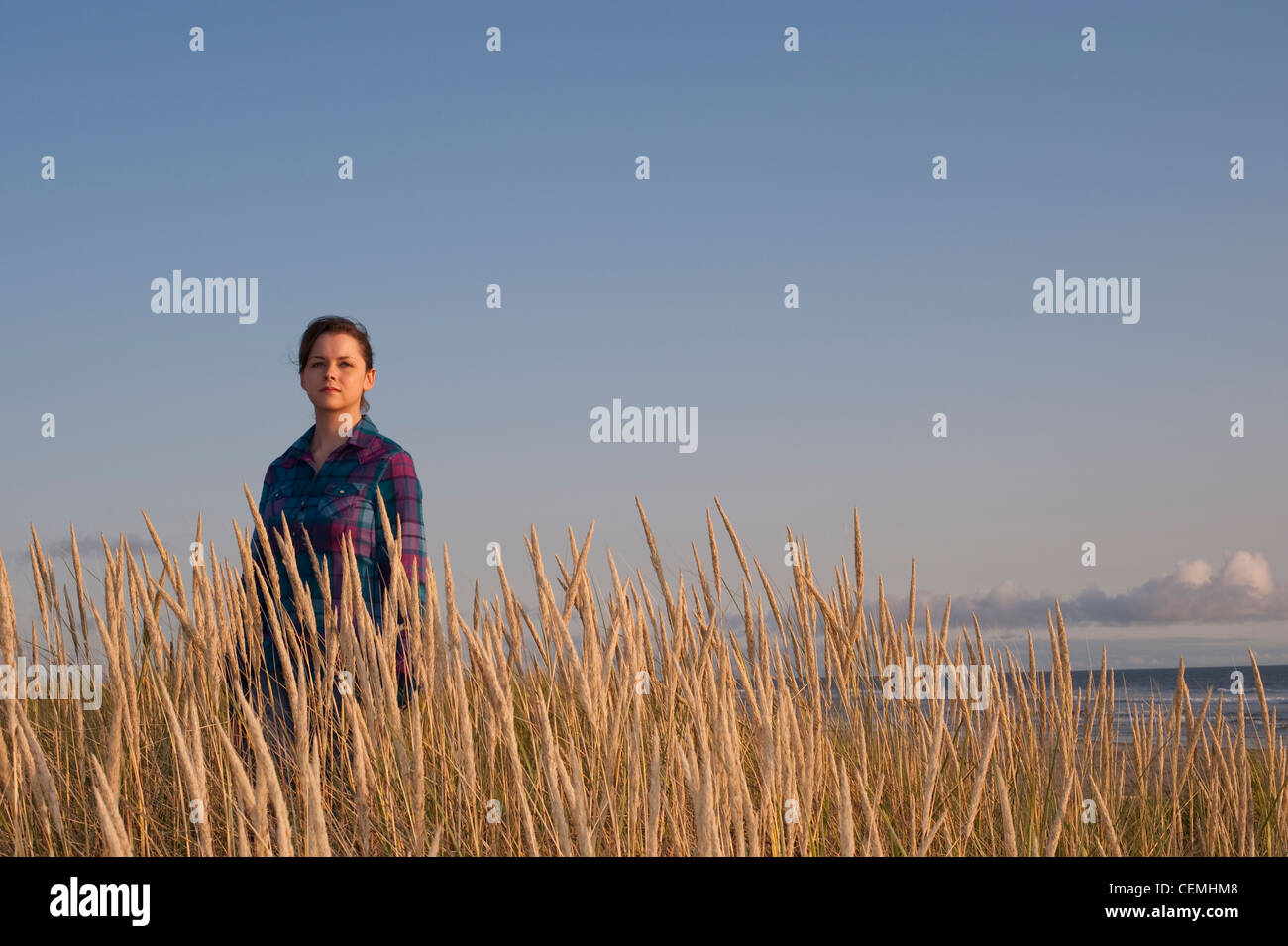 Young woman standing in tall grass sunset portait Stock Photo - Alamy