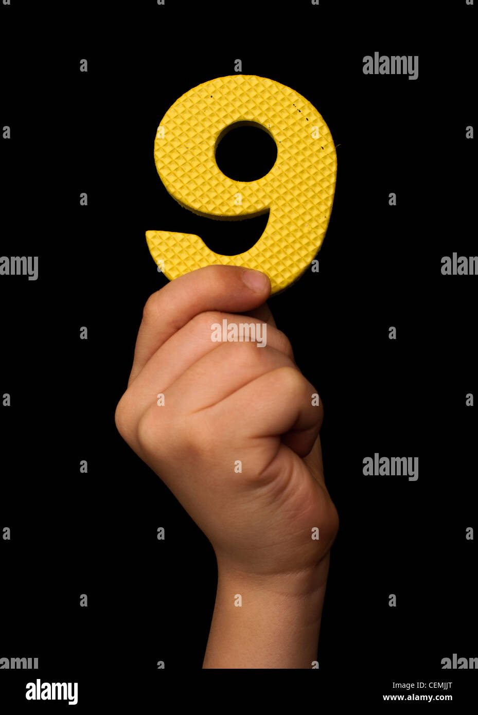 Children hand holding the number Nine. Black isolated yellow color ...
