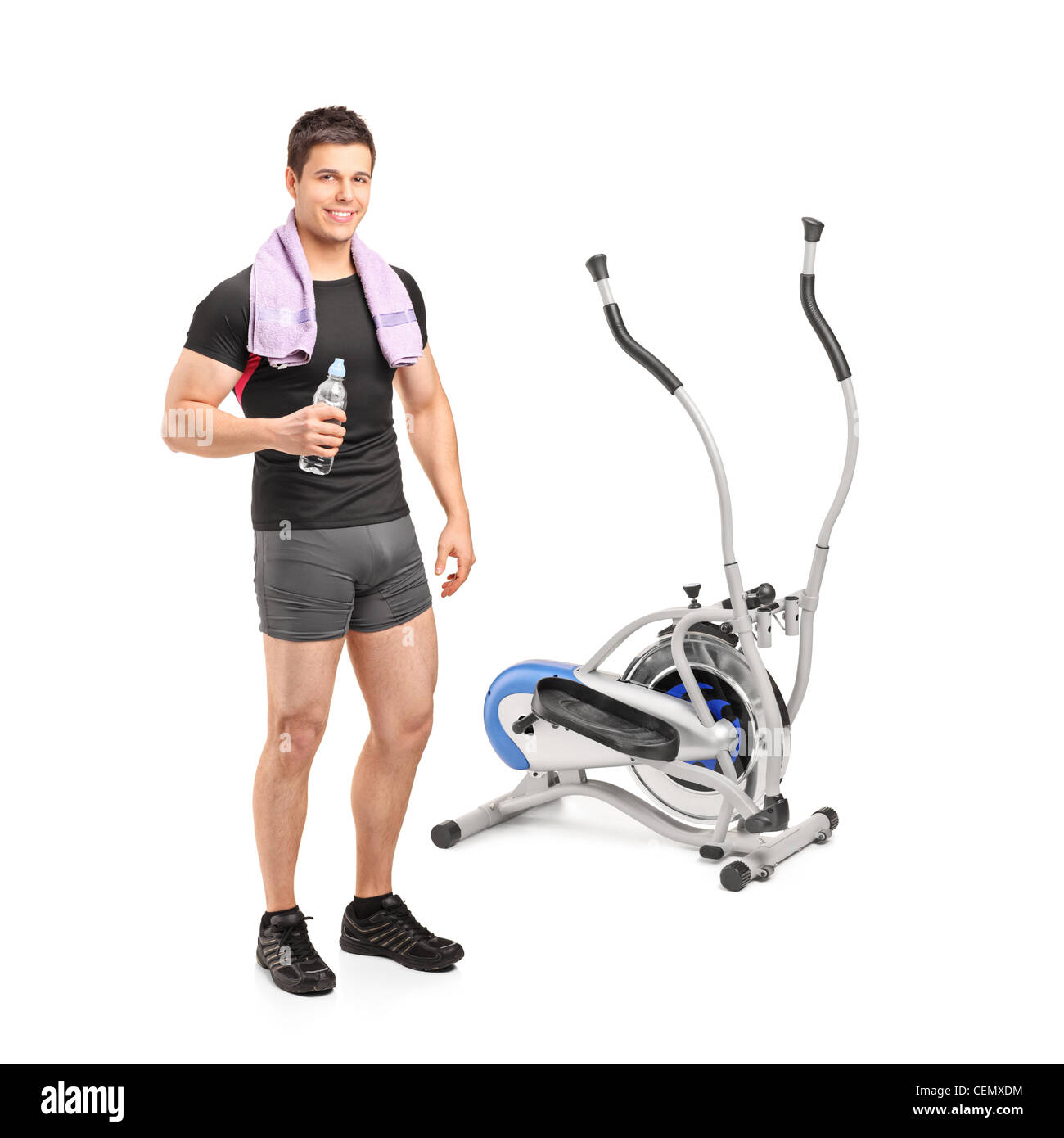 Full length portrait of an athlete standing near a cross trainer ...