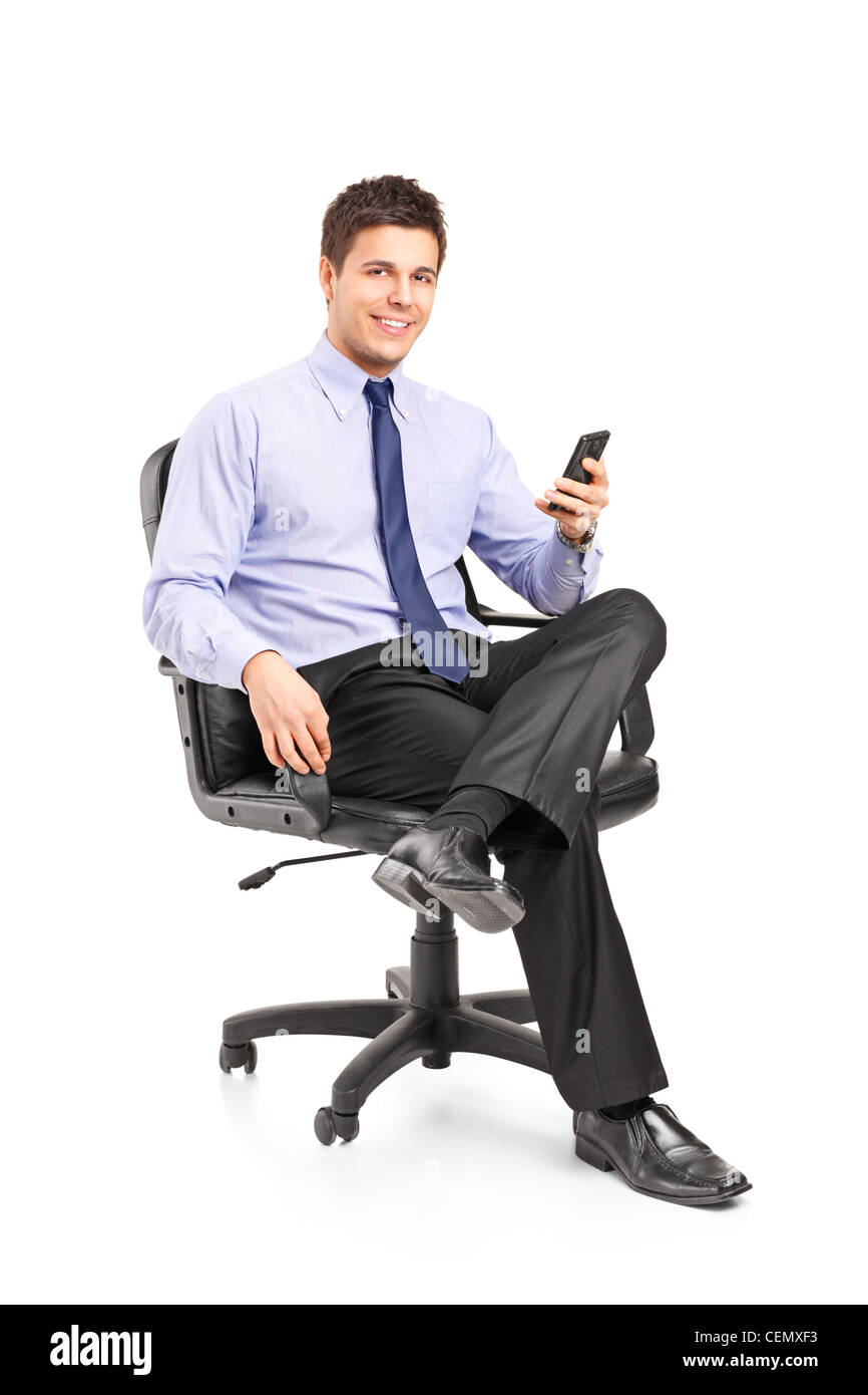 Young businessman sitting on a chair and holding a mobile phone ...