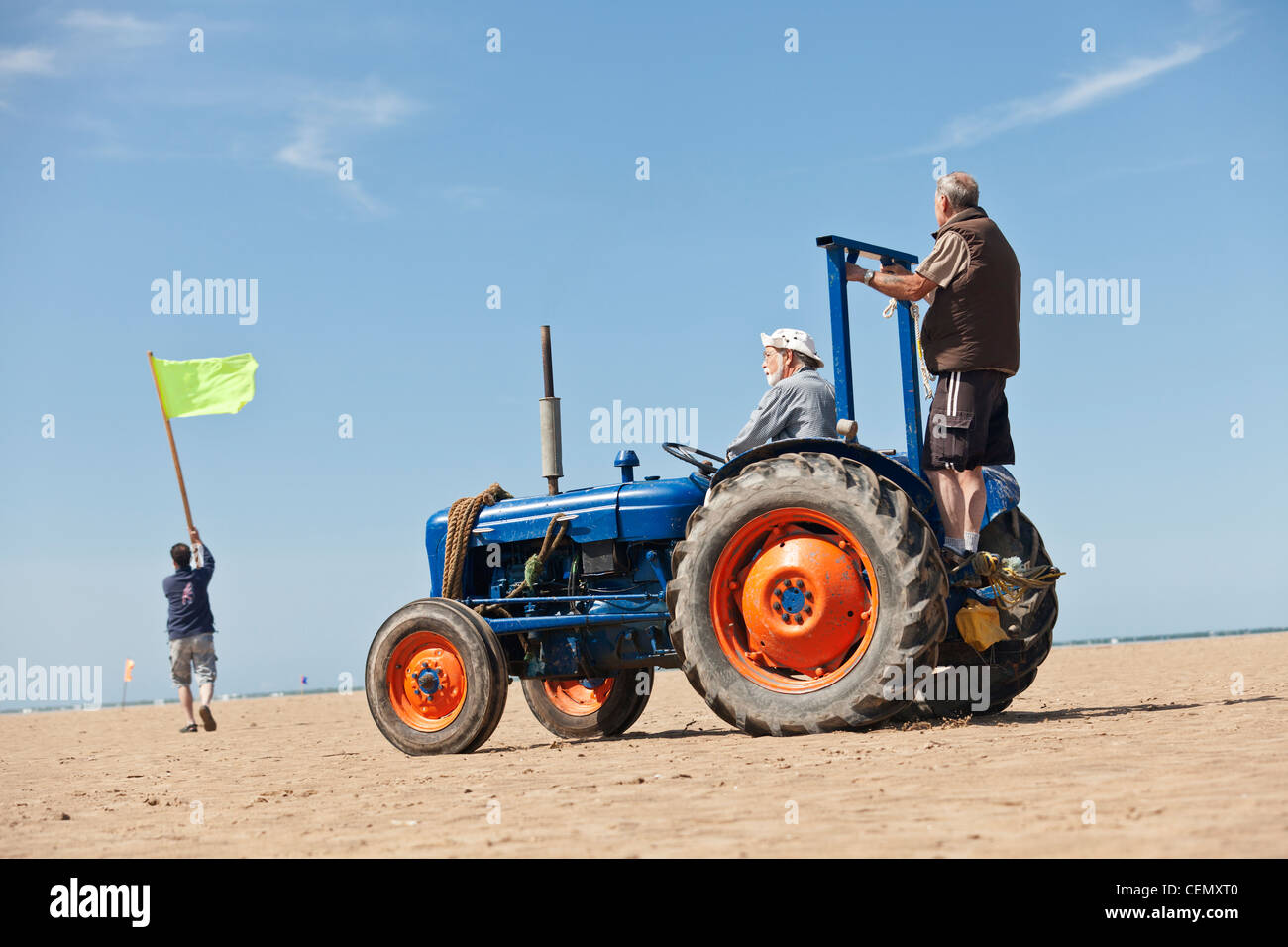 land yacht sailing race officials ride a tractor on the beach with ...