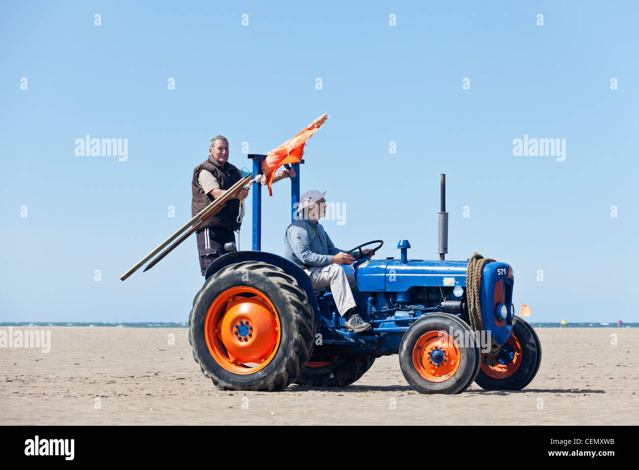 land yacht sailing race officials ride a tractor on the beach with ...