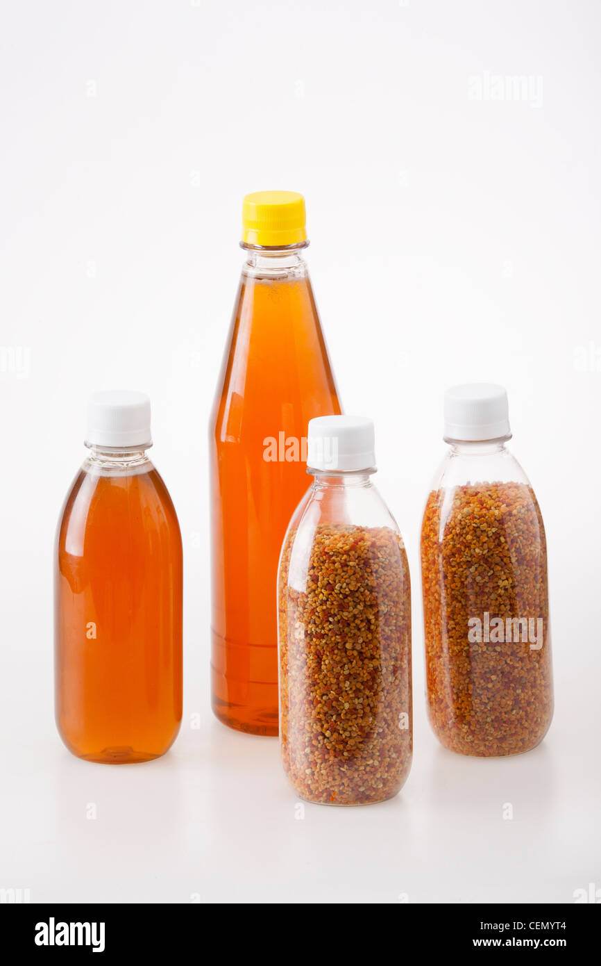 Two bottles of honey, and two bottle of edible pollen on a white ...