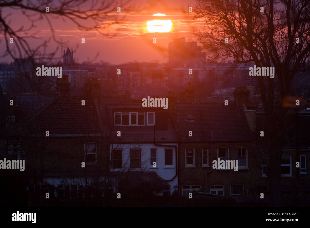 Lens flare from setting sun between layers of cloud over inner-city ...