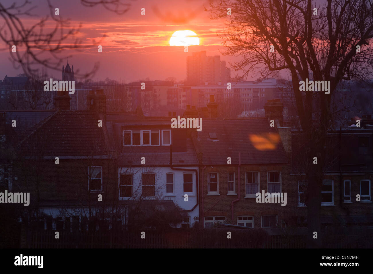 Lens flare from setting sun between layers of cloud over inner-city ...