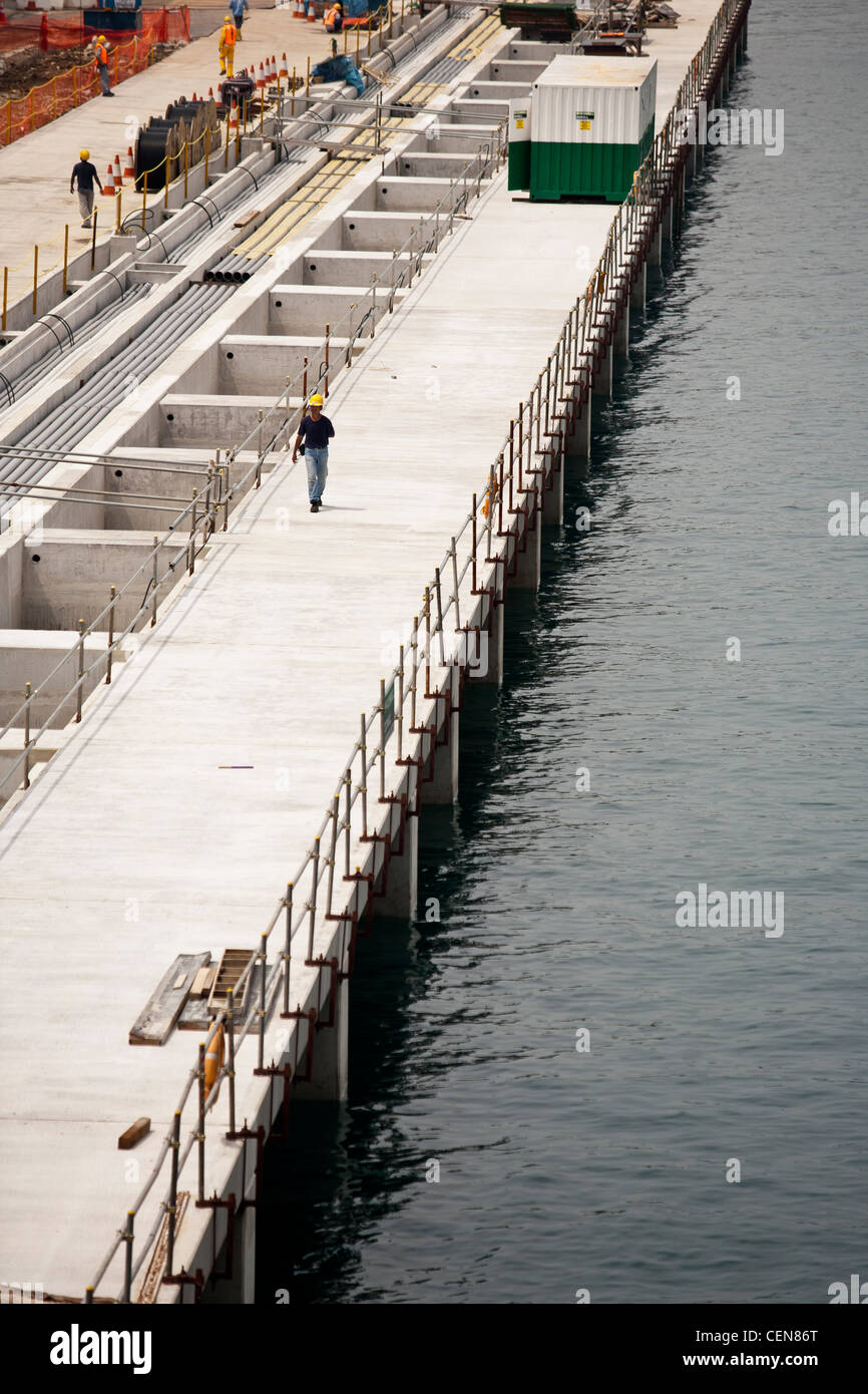 A construction worker walks along the waterfromt at a construction site ...