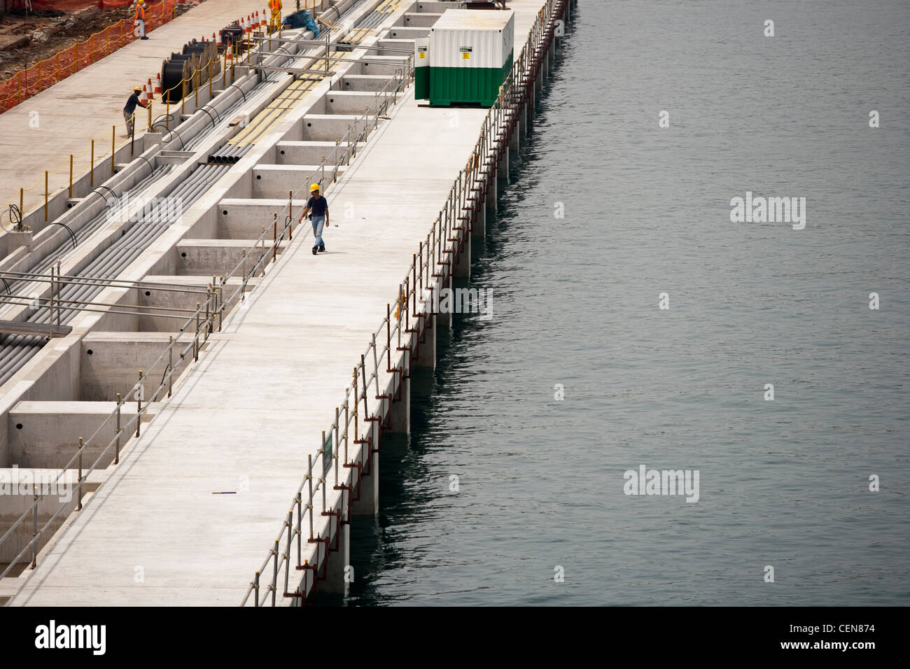 A construction worker walks along the waterfromt at a construction site ...