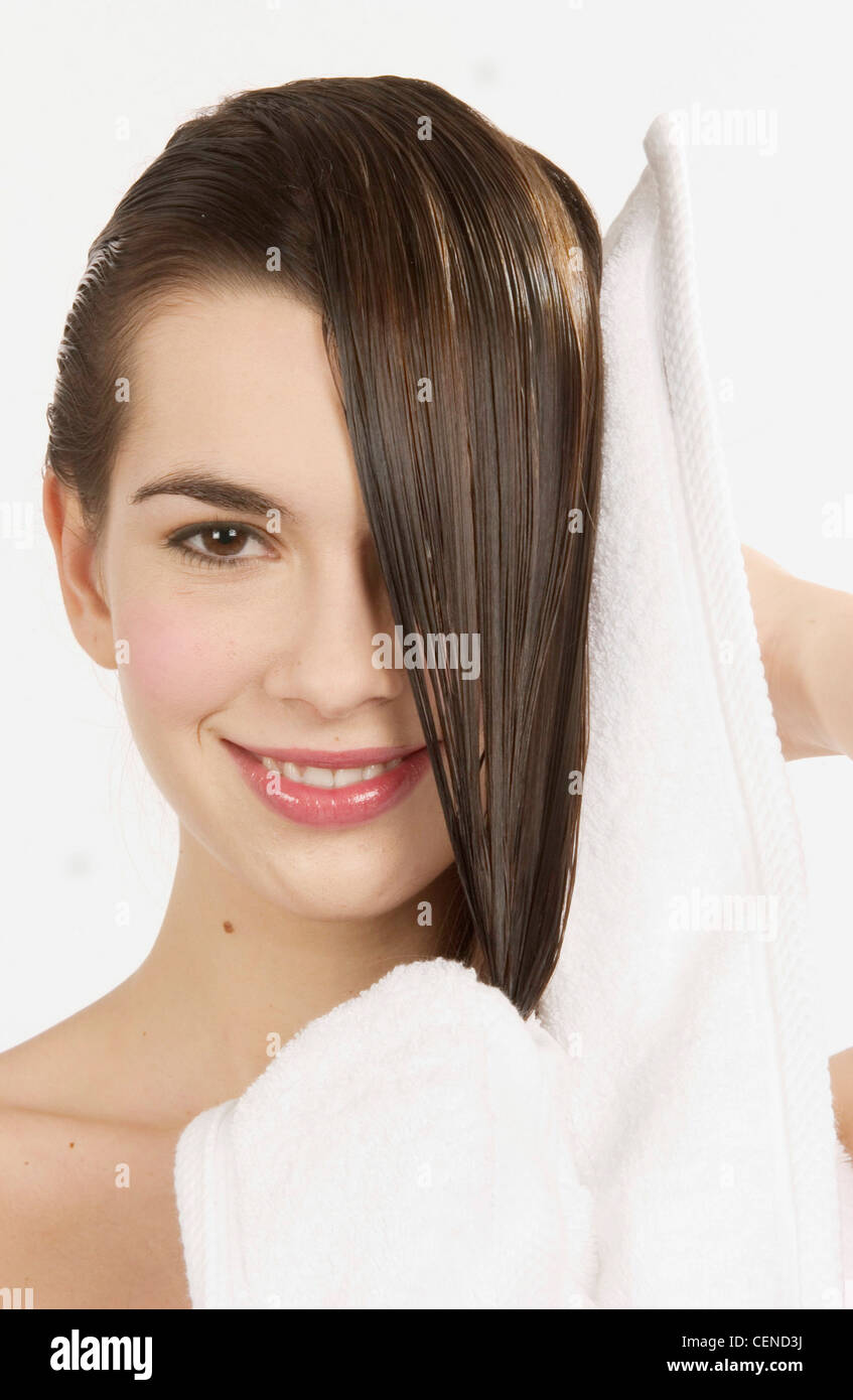 Female with long brunette hair brushed over one eye drying it with ...
