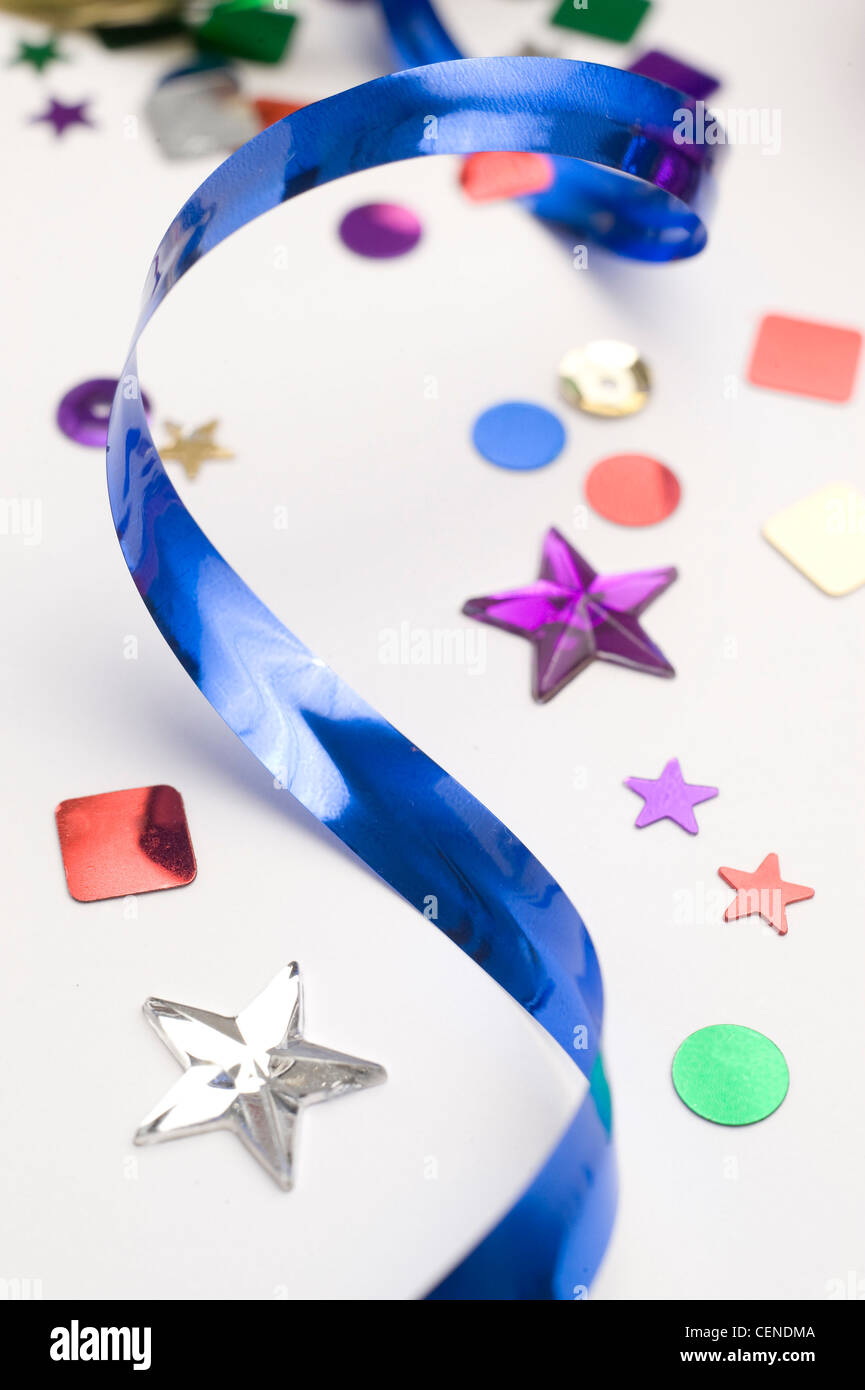 A still life image of colourful confetti and blue streamers on white ...