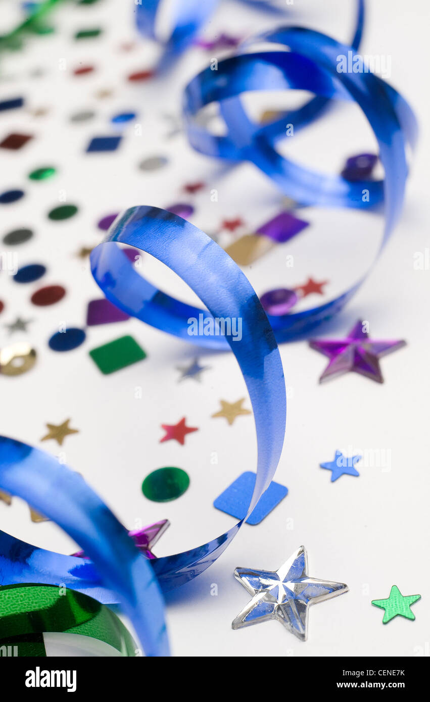 A still life image of colourful confetti and blue streamer on white ...