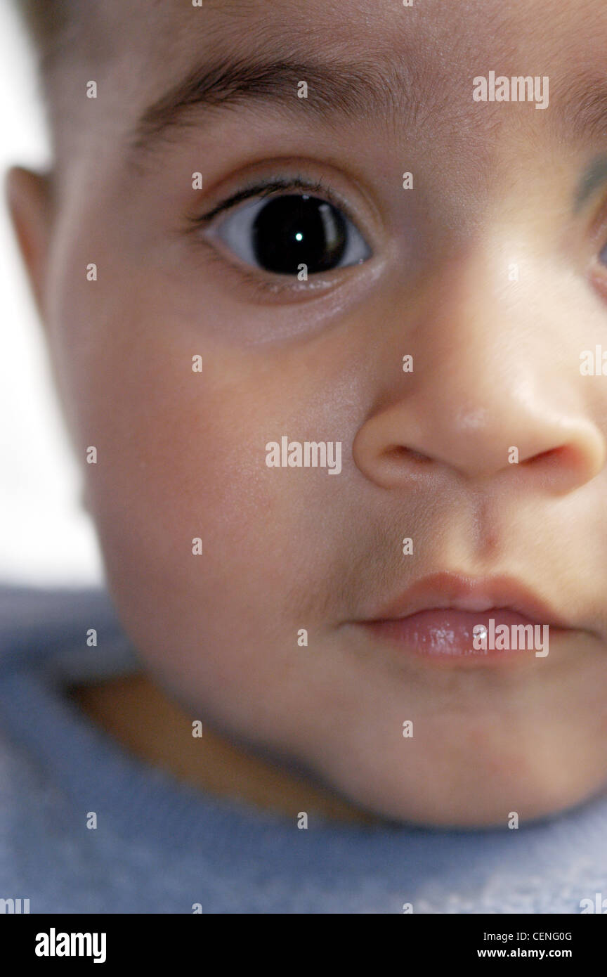 Male child wearing blue looking straight to camera unsmiling, half face ...