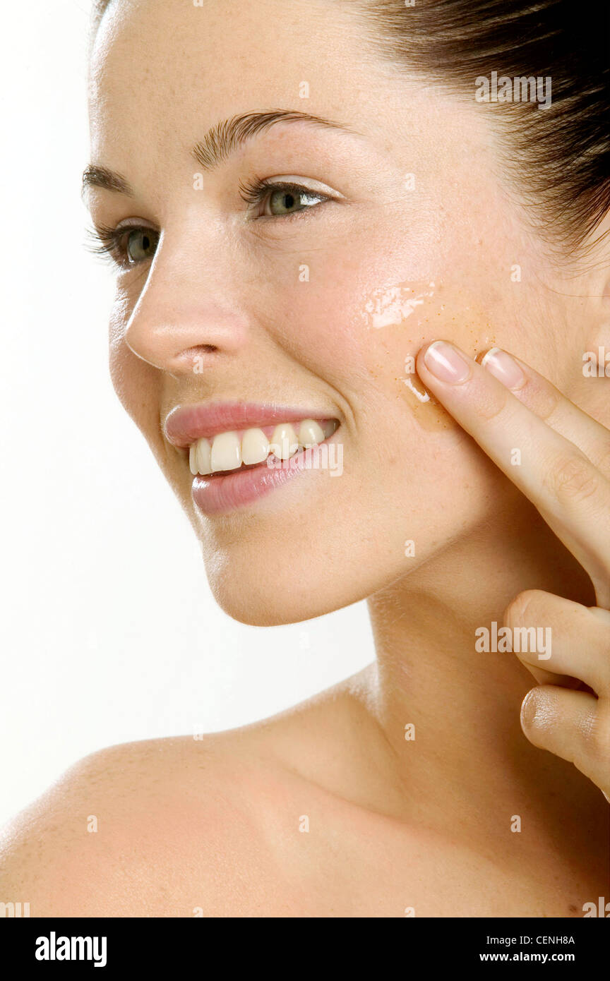 Female rubbing in clear exfoliating gel on to cheek with fingers ...