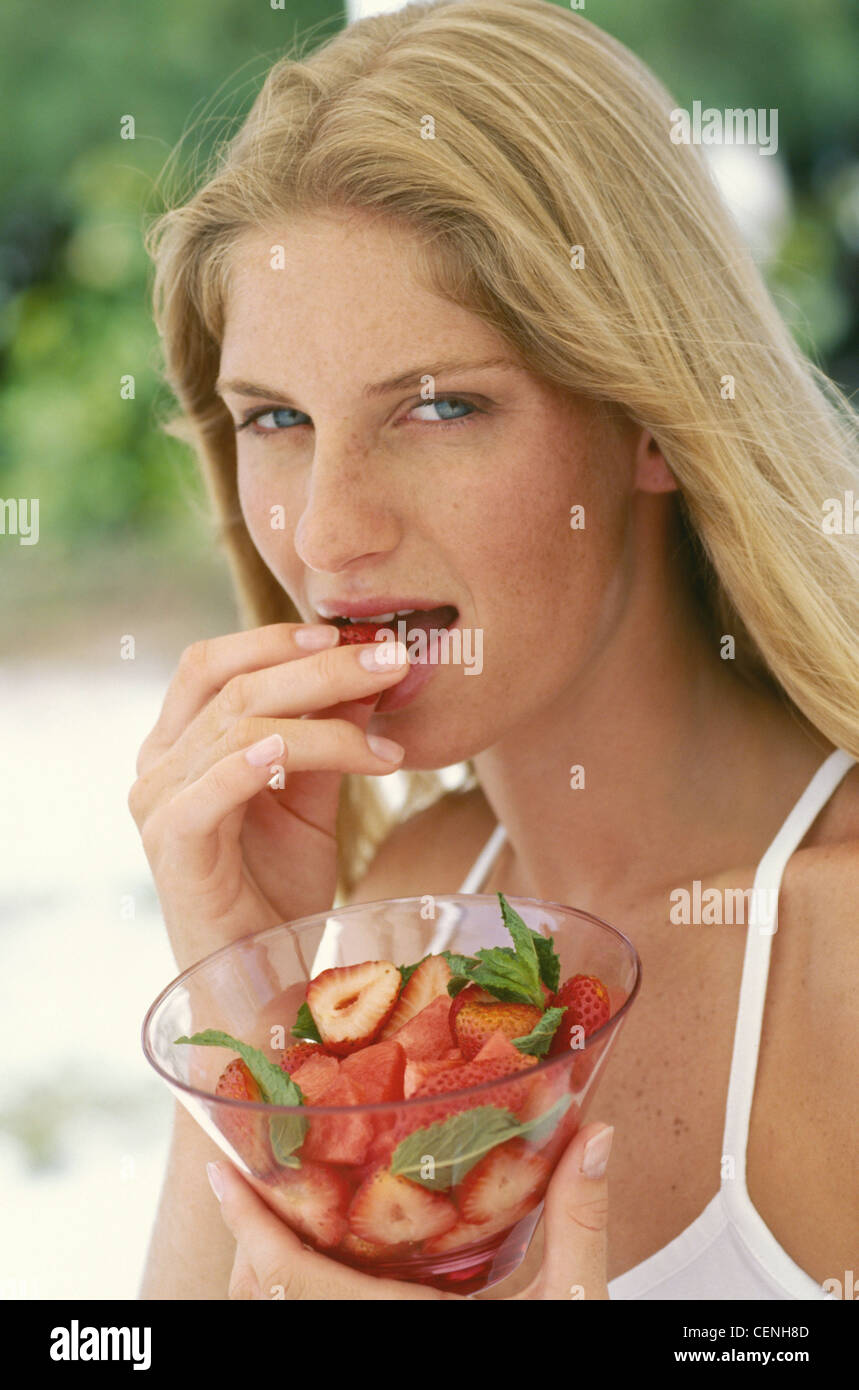 Female Long Blonde Hair Wearing White Vest Top Eating Strawberry And