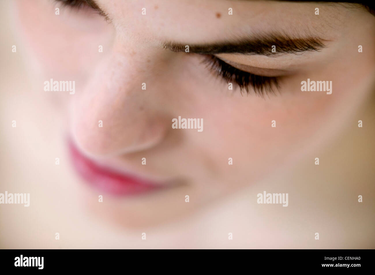 Close up of female face looking down unsmiling, against white ...
