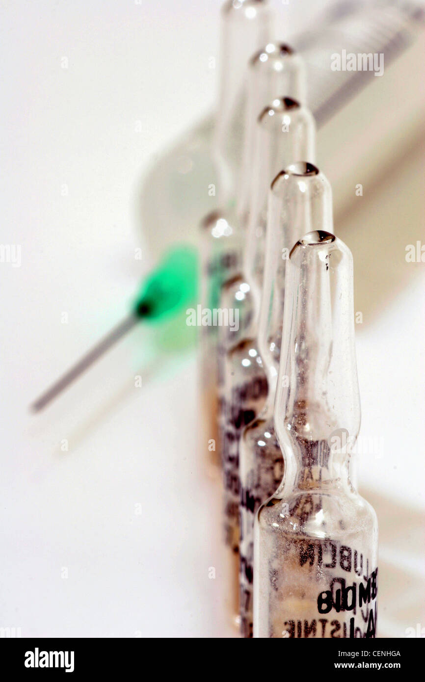 A line of some clear glass sealed vials, with a needle attached to a ...