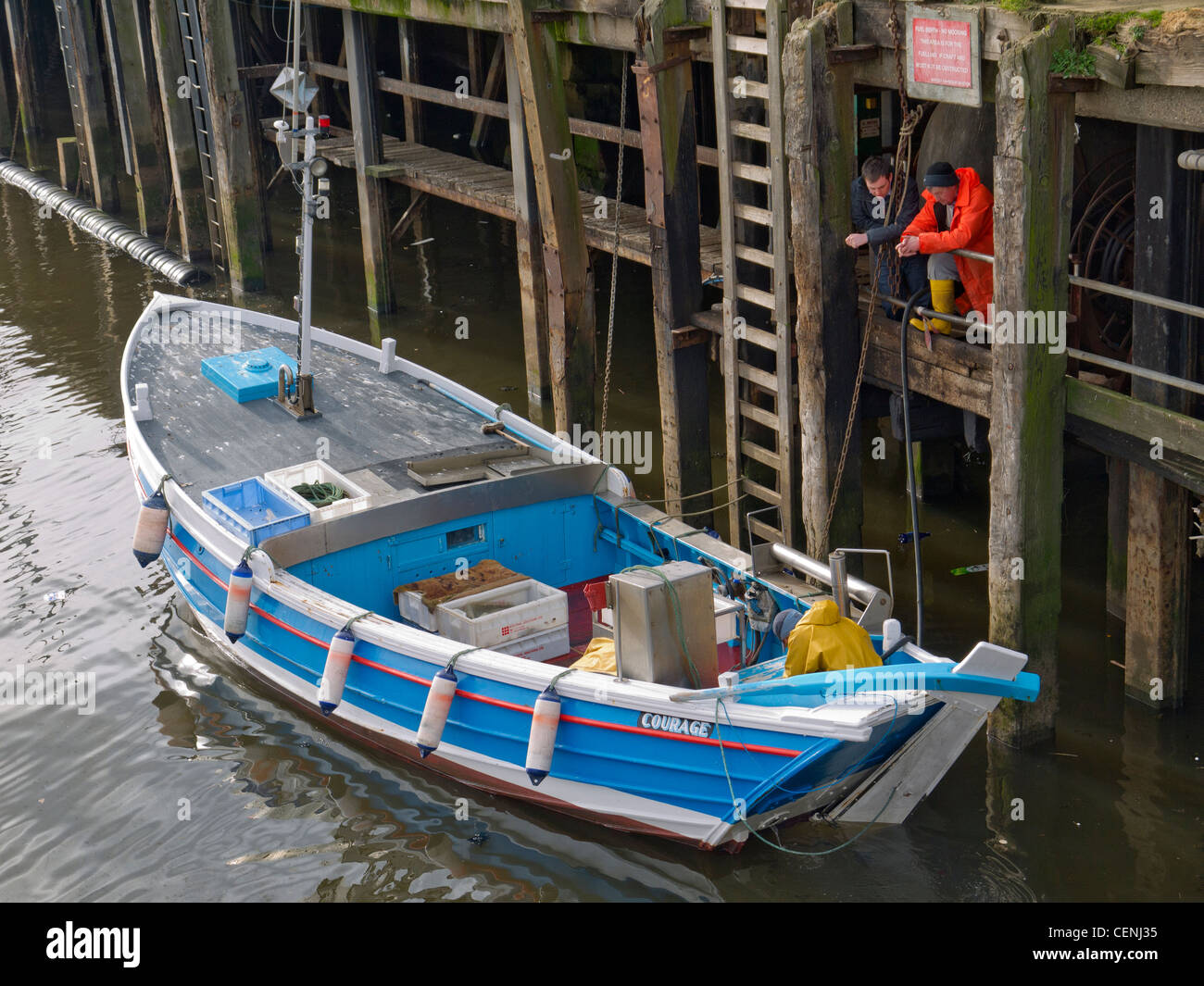 Two fisherman with a fishing coble just arrived at Whitby waiting to ...