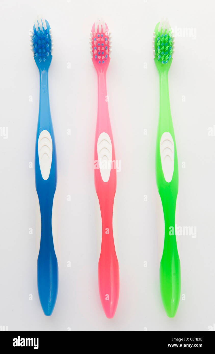 Three brightly coloured toothbrushes, blue, pink and green in a line ...