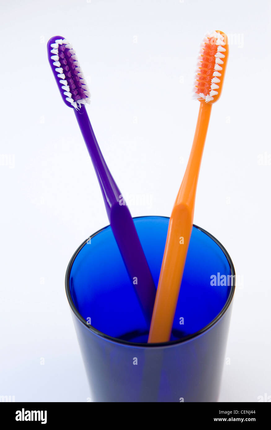 A blue glass with a purple toothbrush and yellow toothbrush in it Stock ...