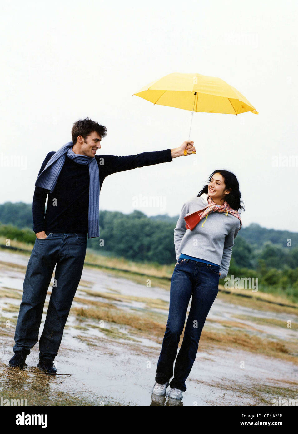 Couple standing side by side in a muddy grass slightly apart looking at ...
