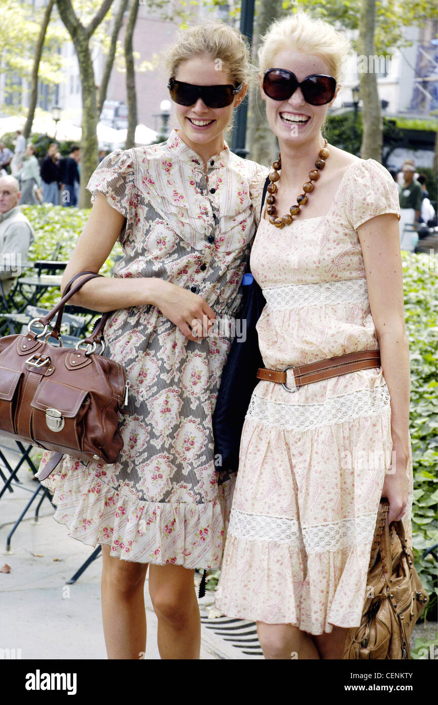 Two blonde models their hair pulled back standing together relaxing in ...