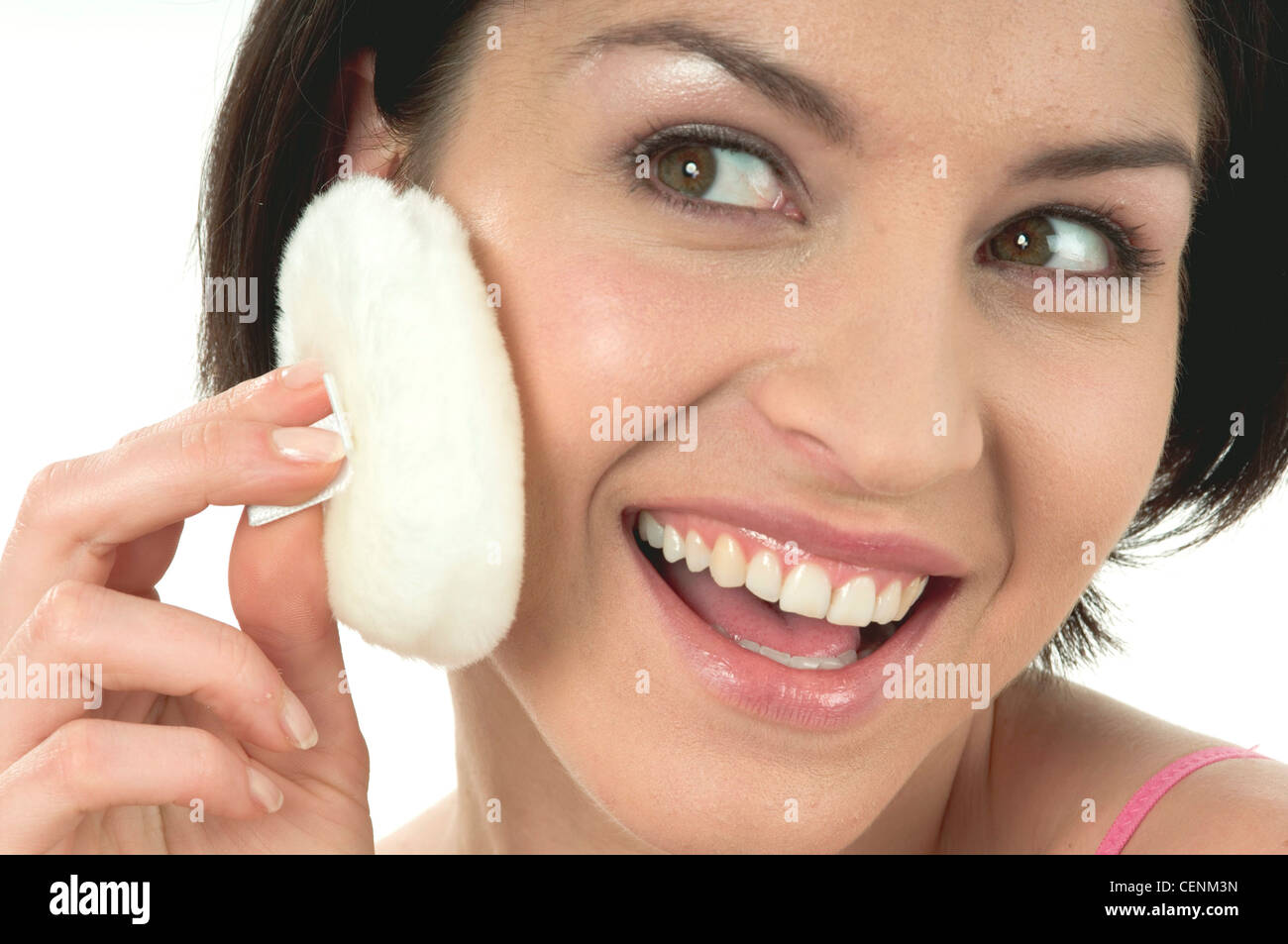 Close up of female holding powder puff to cheek looking sideways mouth ...