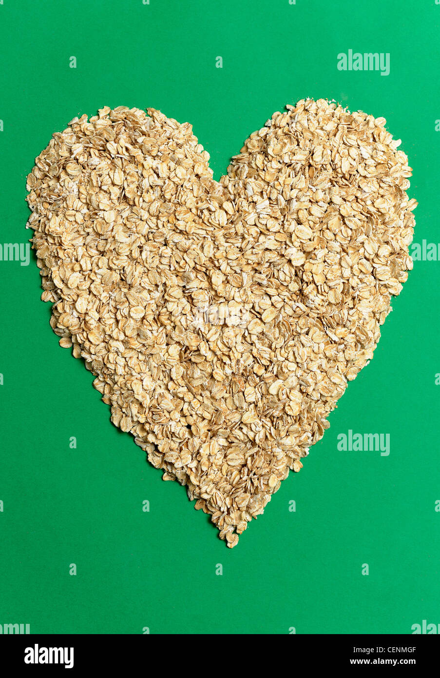 A still life image of dry porridge oats in heart shape on green ...