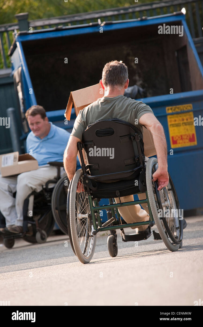 Men in wheelchairs moving trash to the dumpster Stock Photo - Alamy
