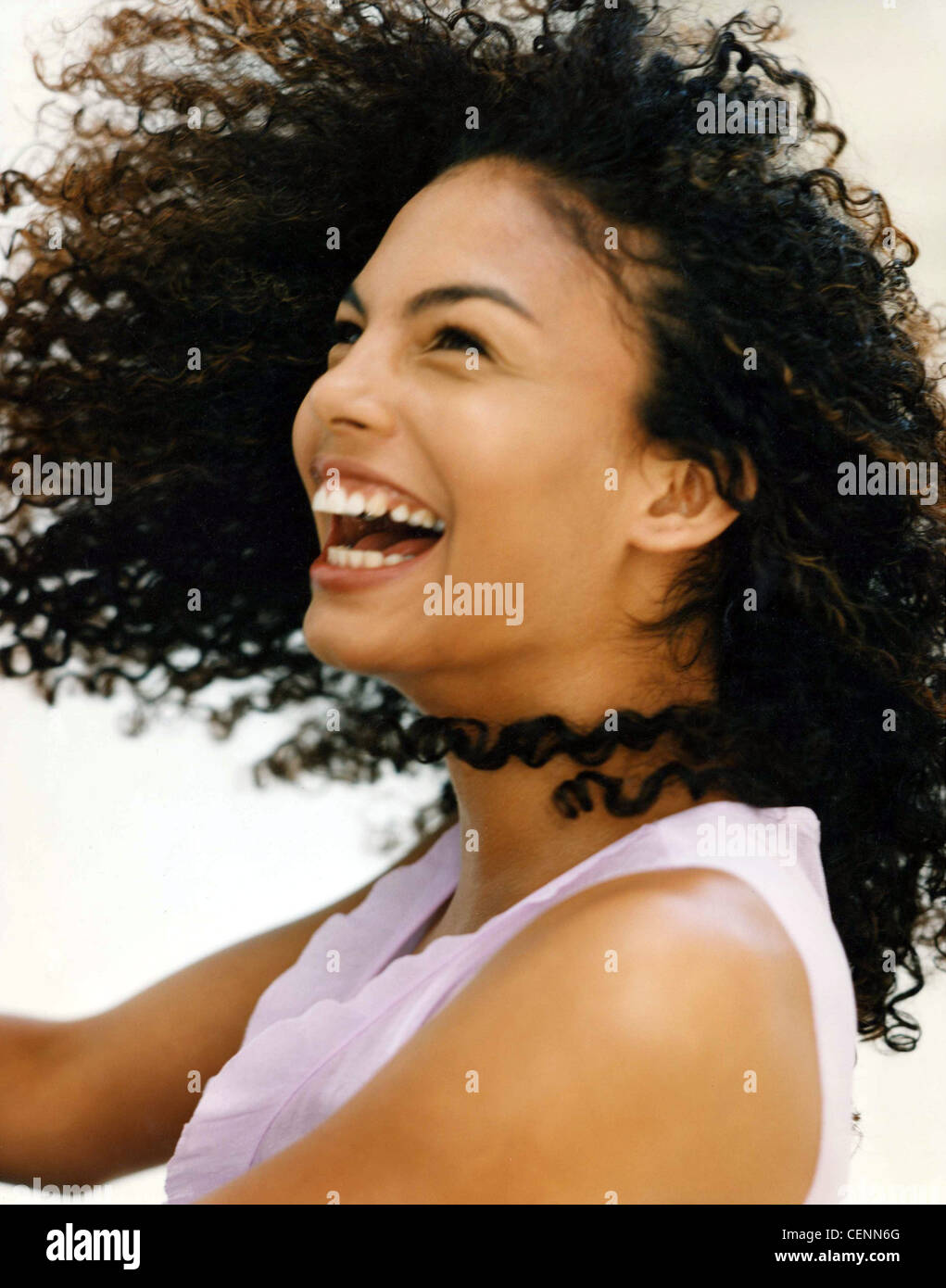 Brunette female curly hair wearing a white sleeveless top, standing ...