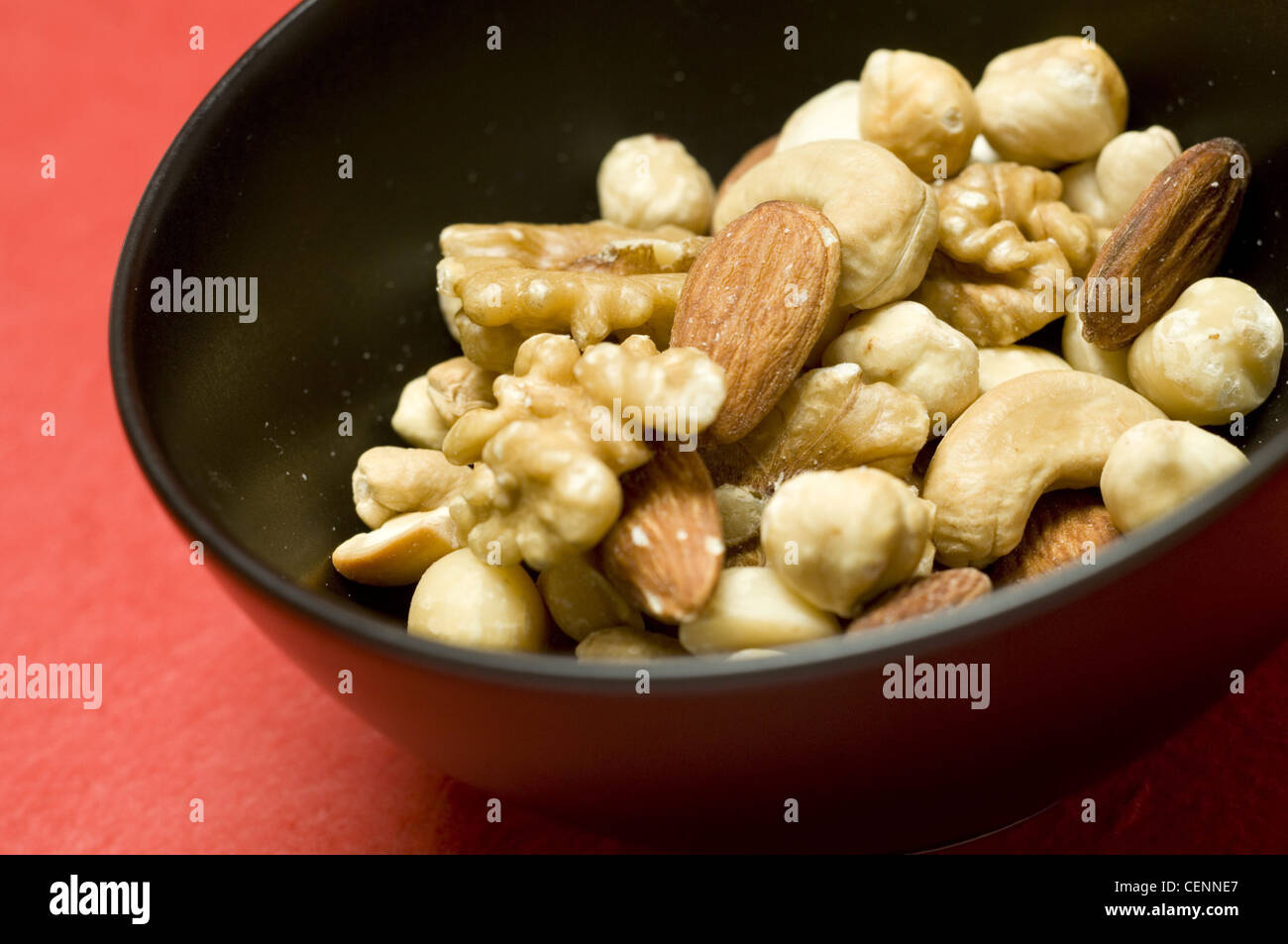 Aerial of mixed nuts in red ceramic bowl with dark interior, pictured ...