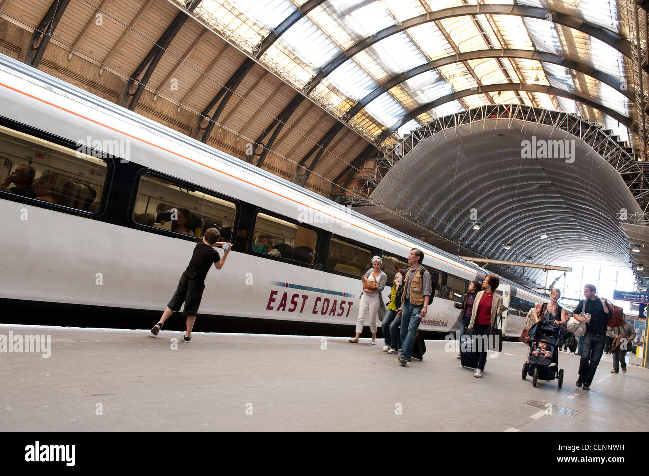 Passengers walking down a platform alongside an East Coast train at a ...